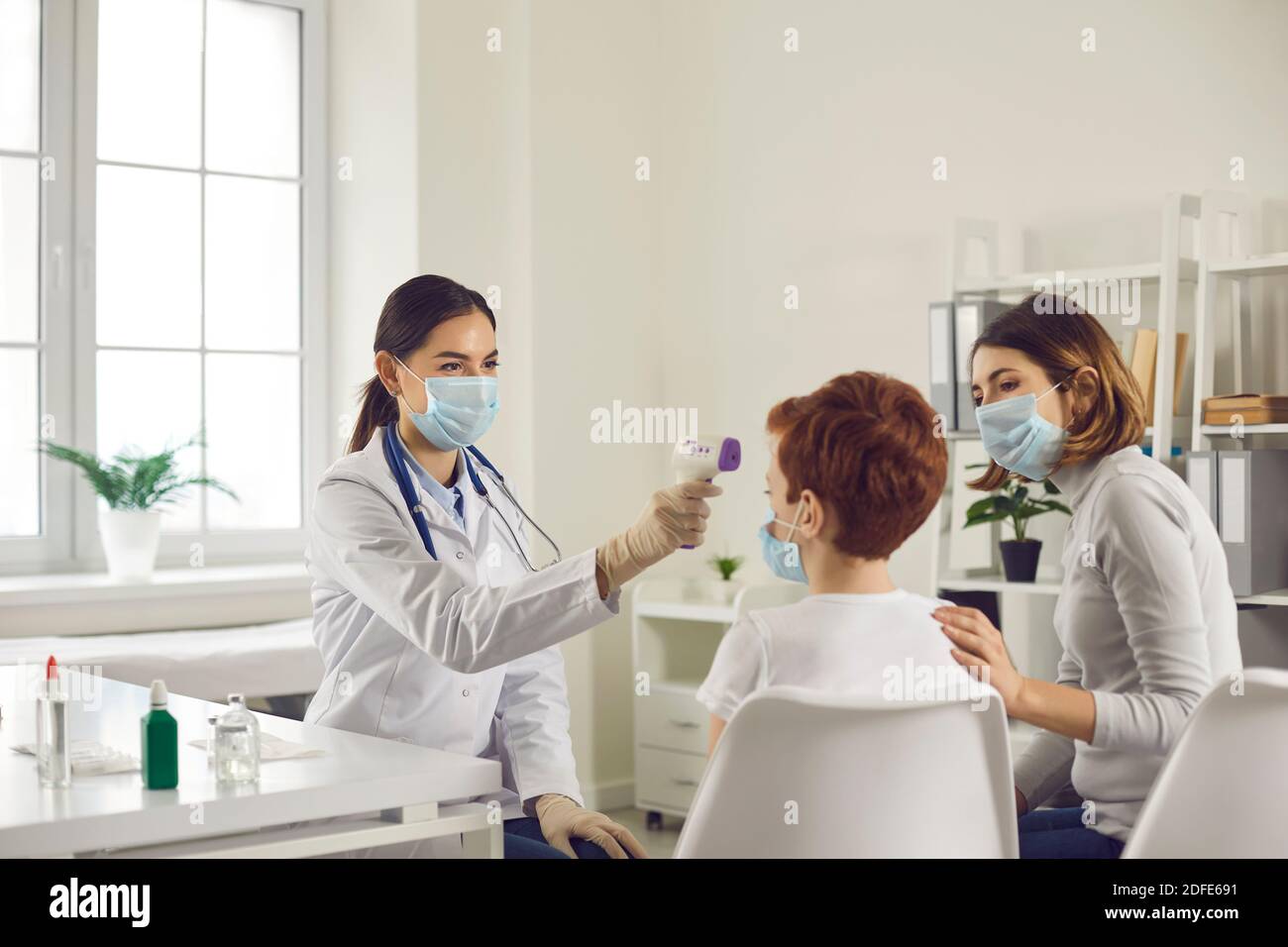 Friendly doctor measuring little child's temperature with non-contact ...