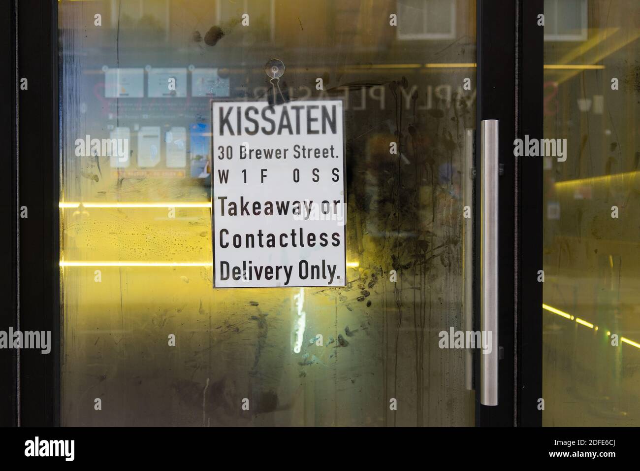 Steamy restaurant shop window with a takeaway delivery sign hanging on ...