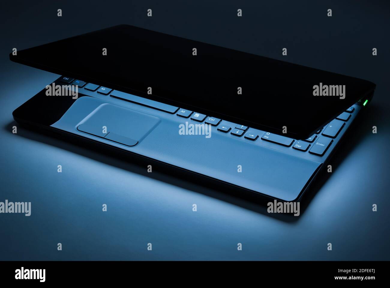 The covered laptop computer with the light shining from the display in ...