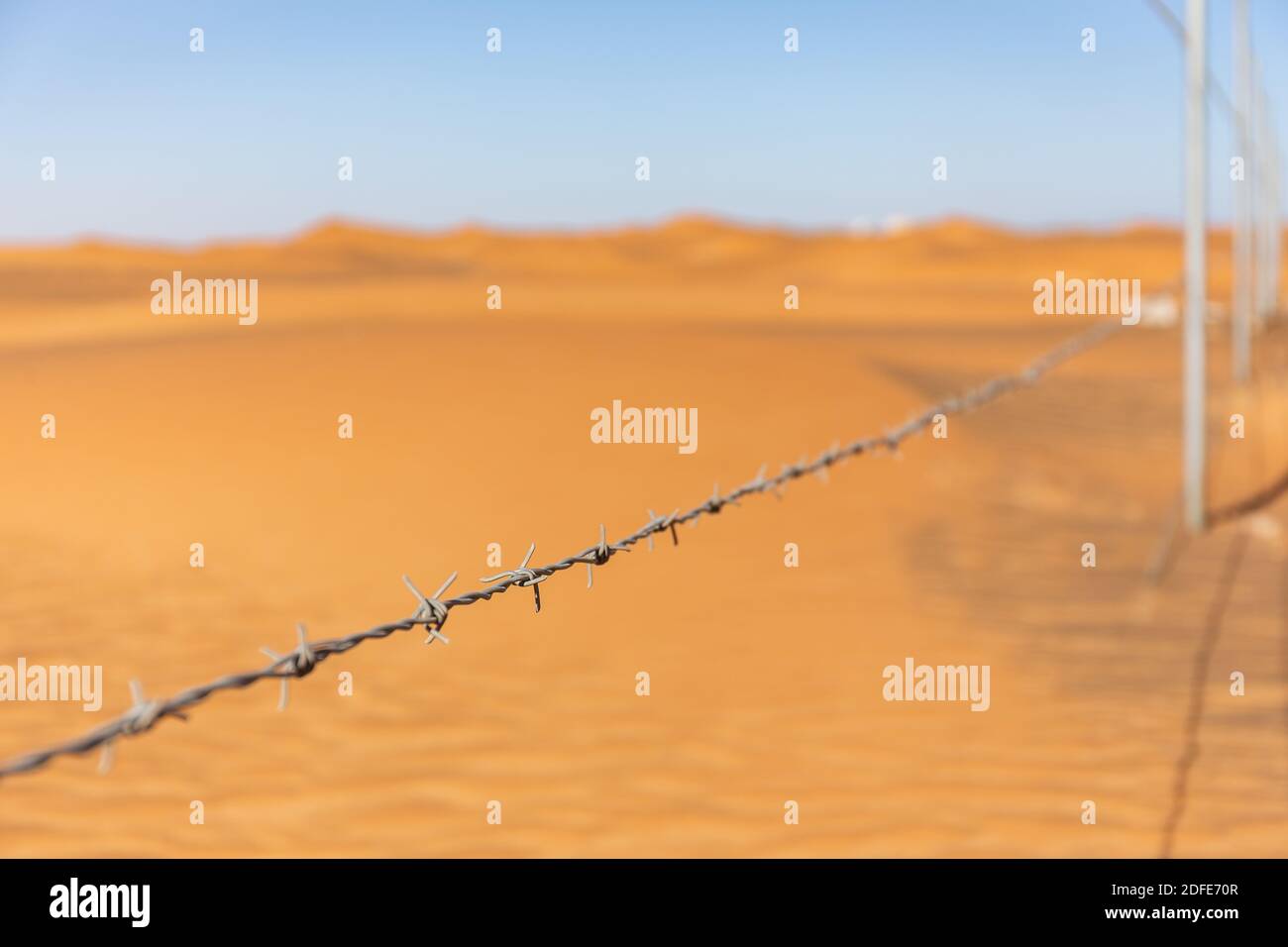 Single barbed wire with desert dunes in the background in Al Madam ...