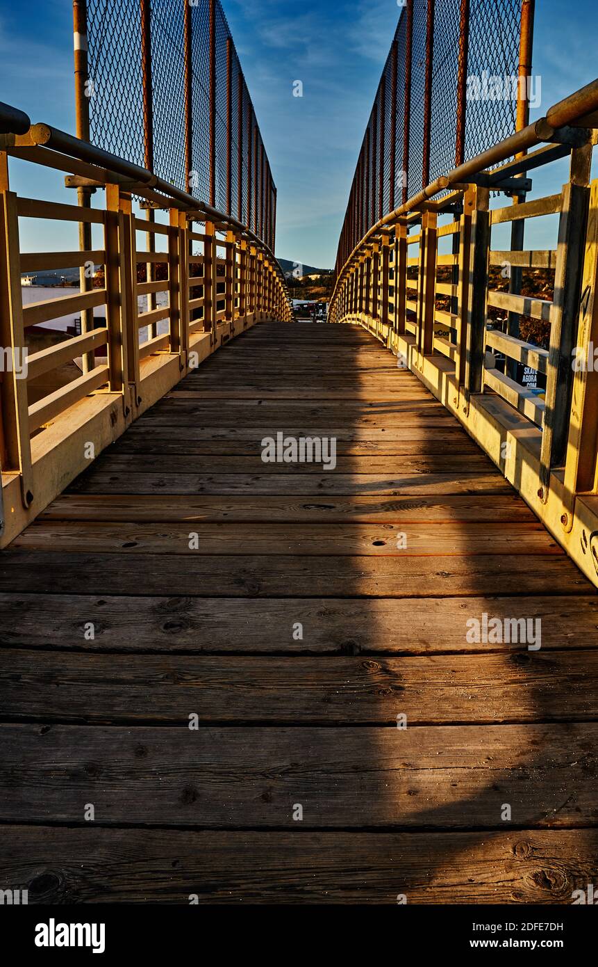 Perspective of a bridge with focus on the wooden floor and metal fence ...