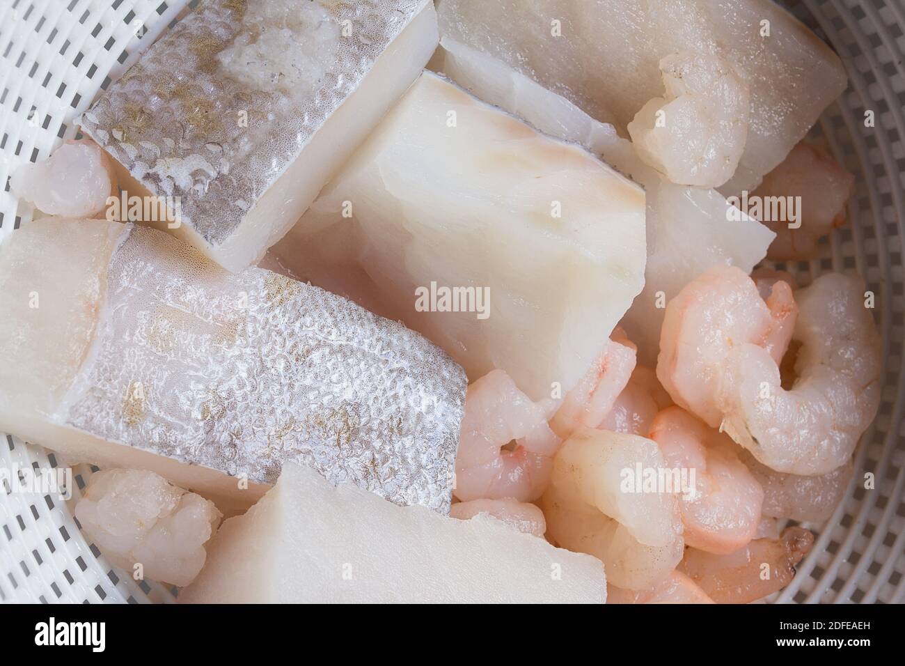 Several fresh cod fillets mixed with prawns on a micro-perforated ...
