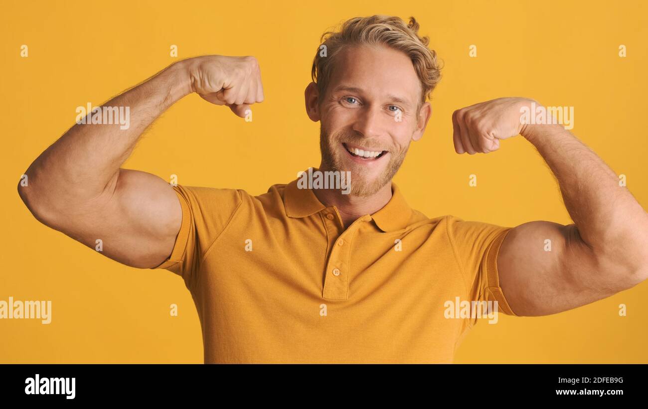 Positive strong bearded guy looking happy showing biceps muscles on ...