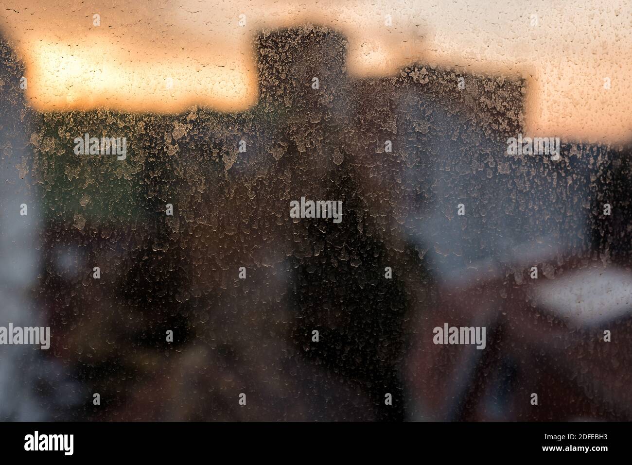 Dirty window glass with dust and dried raindrops backlit with a sunset ...