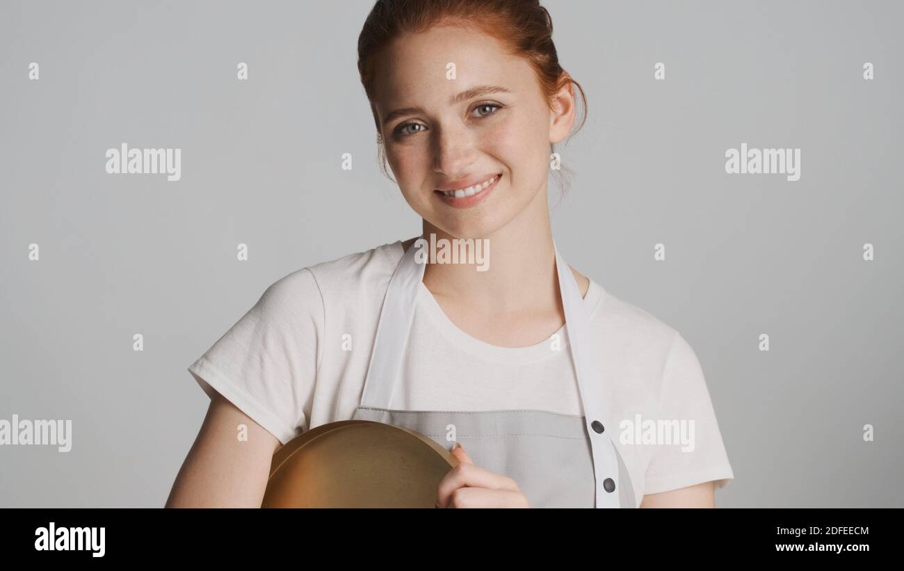 Beautiful waitress in apron with tray happily posing on camera over ...