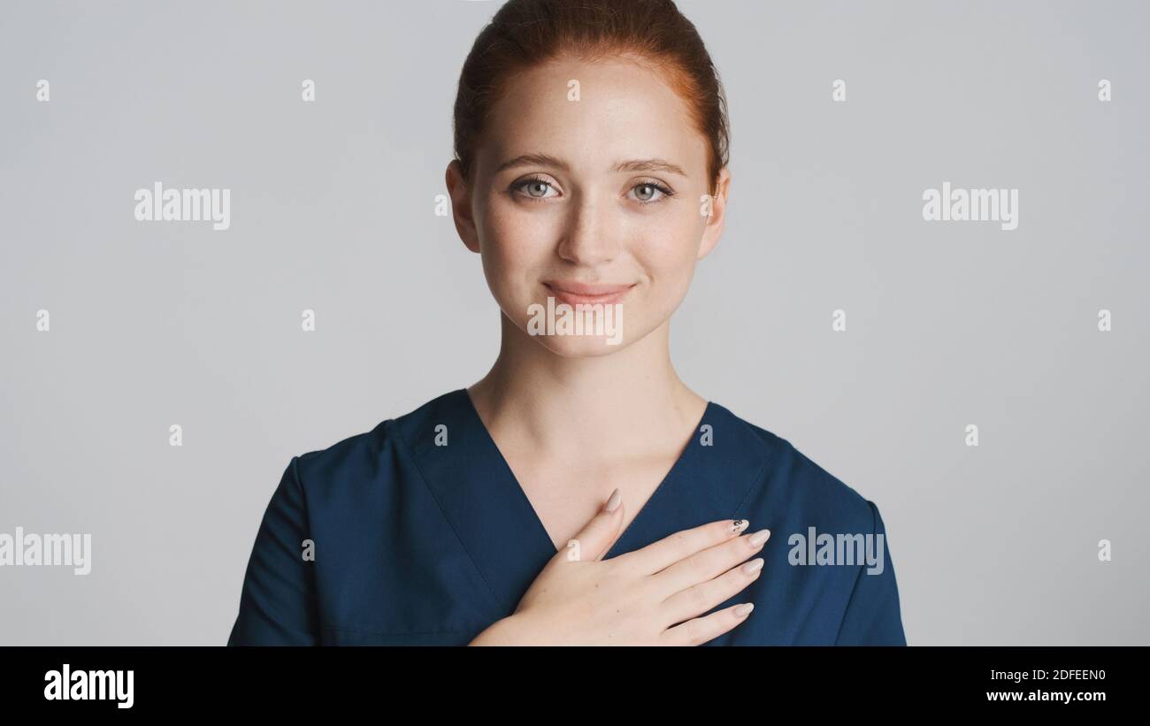 Attractive doctor holding hand on heart dreamily looking in camera ...