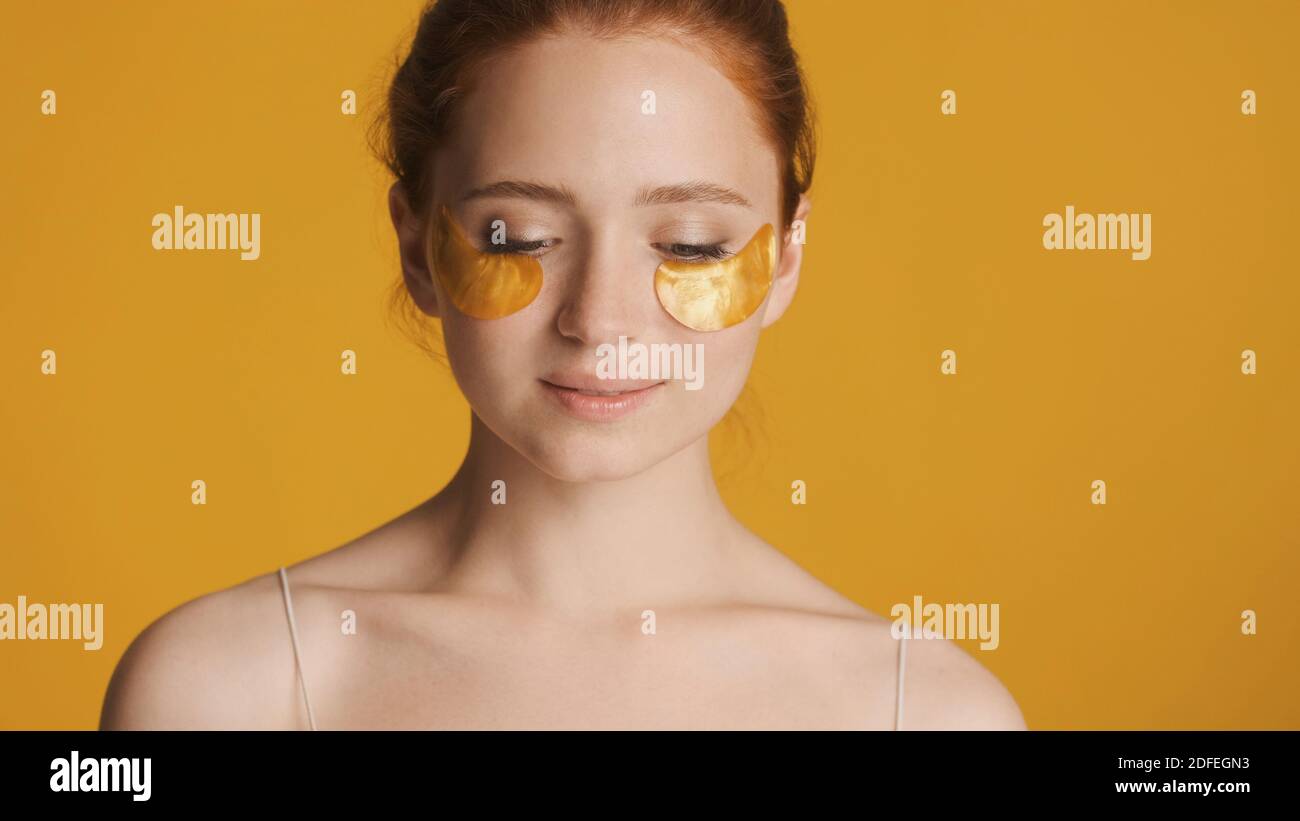 Attractive girl in eye patches dreamily posing on camera over colorful ...