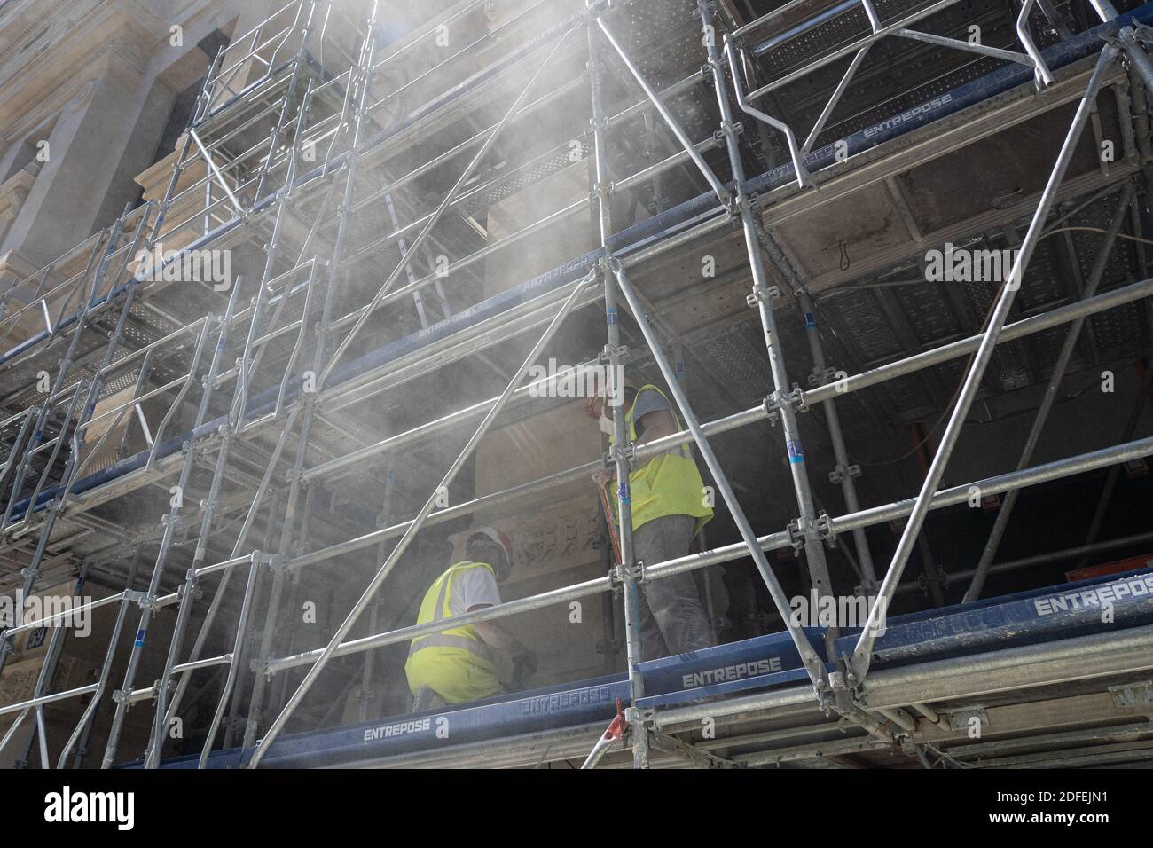 Workers on the facade of the Poste du Louvre building that is under ...