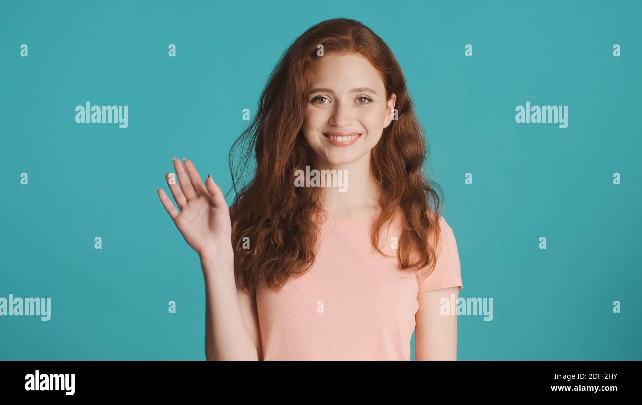 Beautiful girl smiling and happily waving hello on camera over colorful ...