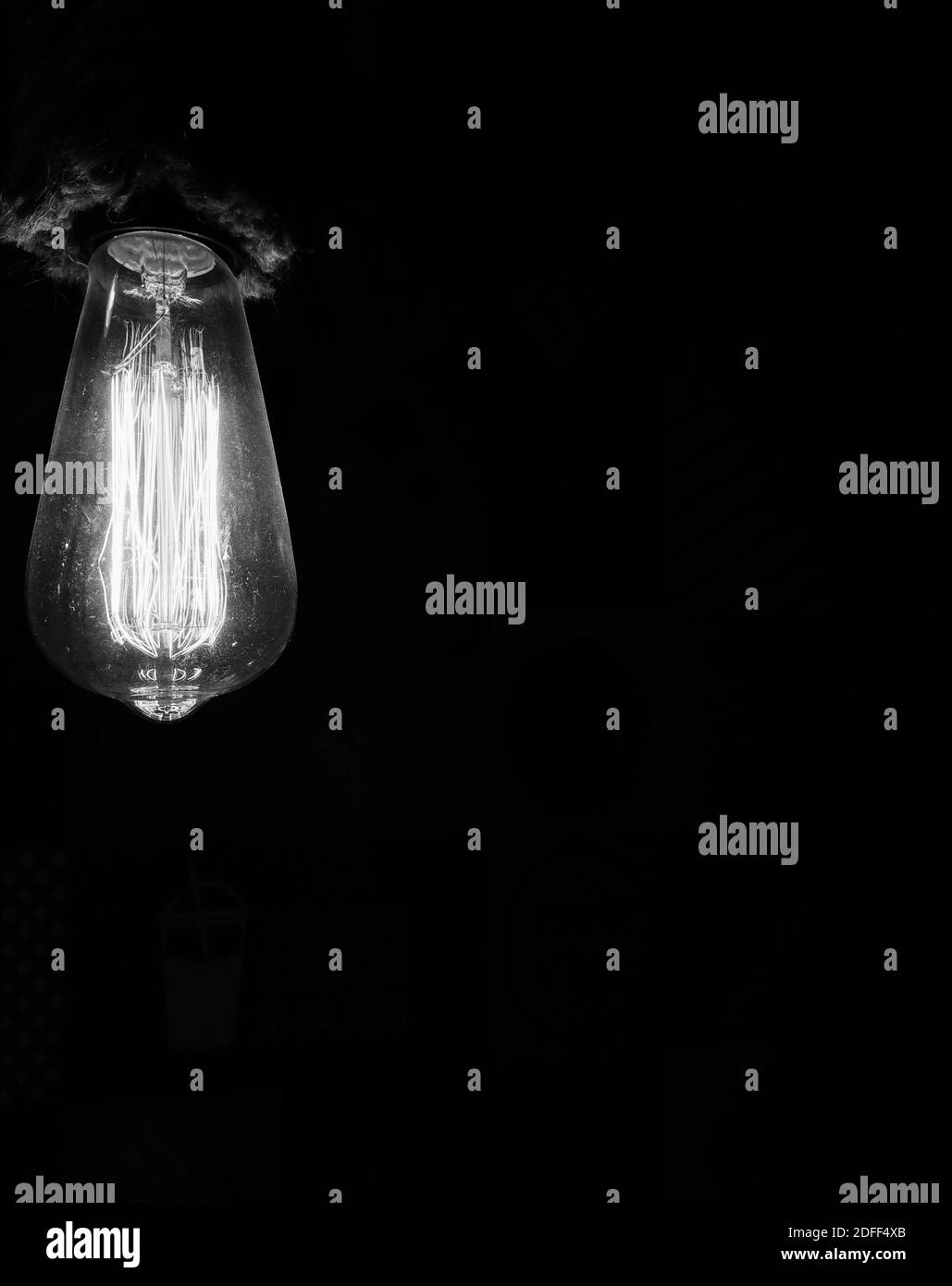 A vertical grayscale of an illuminated Edison light bulb Stock Photo ...