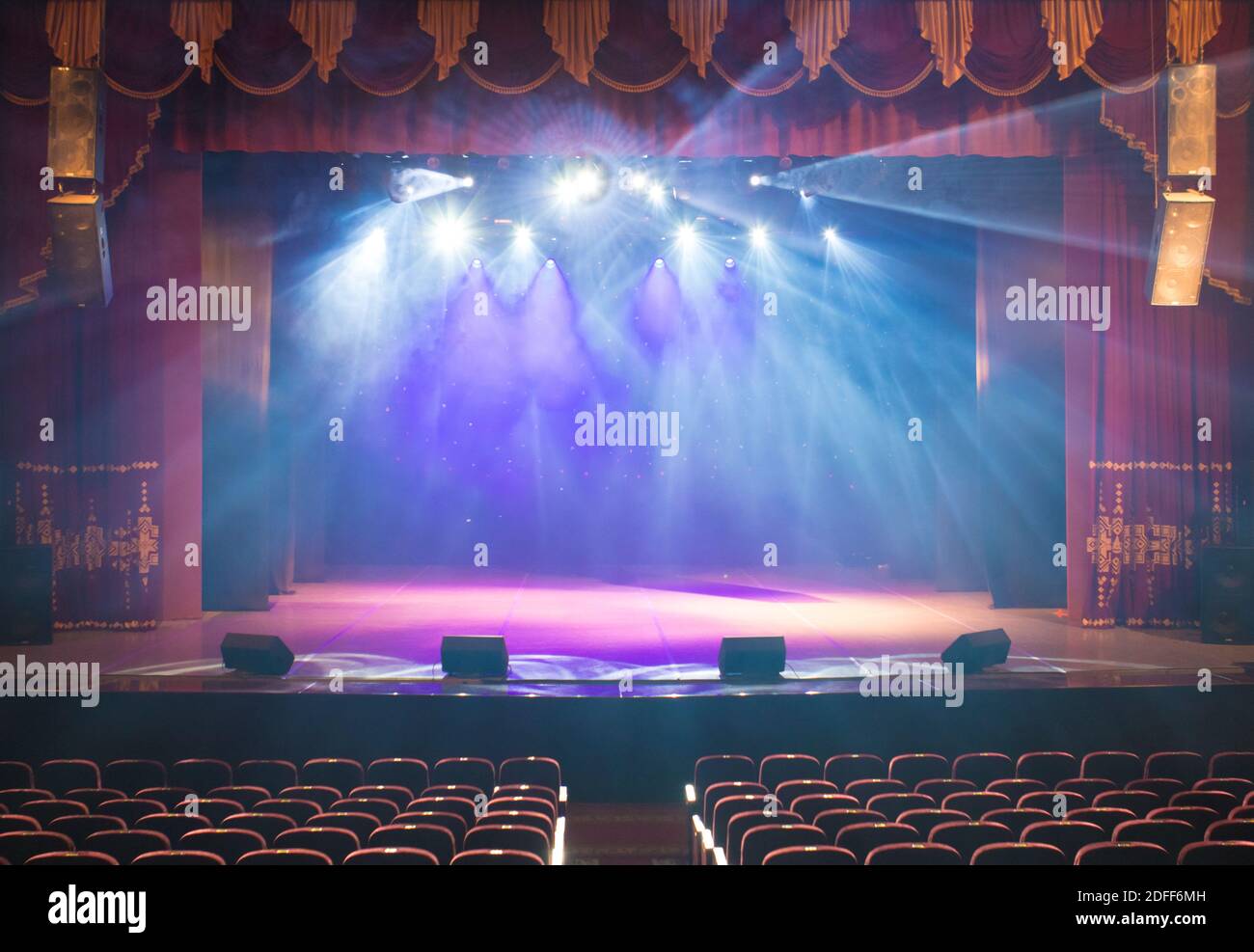 An empty stage of the theater, lit by spotlights and smoke before the ...