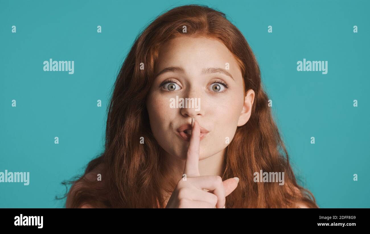 Attractive Excited Girl Telling Secret Showing Silence Gesture On Camera Over Colorful