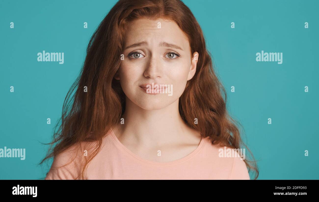 Attractive worry girl sadly looking in camera over colorful background ...