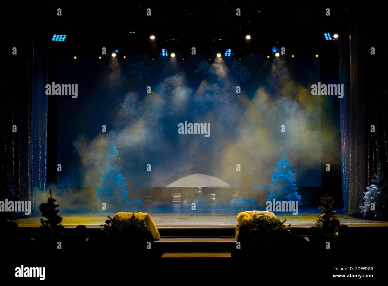 A theater stage with a curtain illuminated by stage light and smoke ...