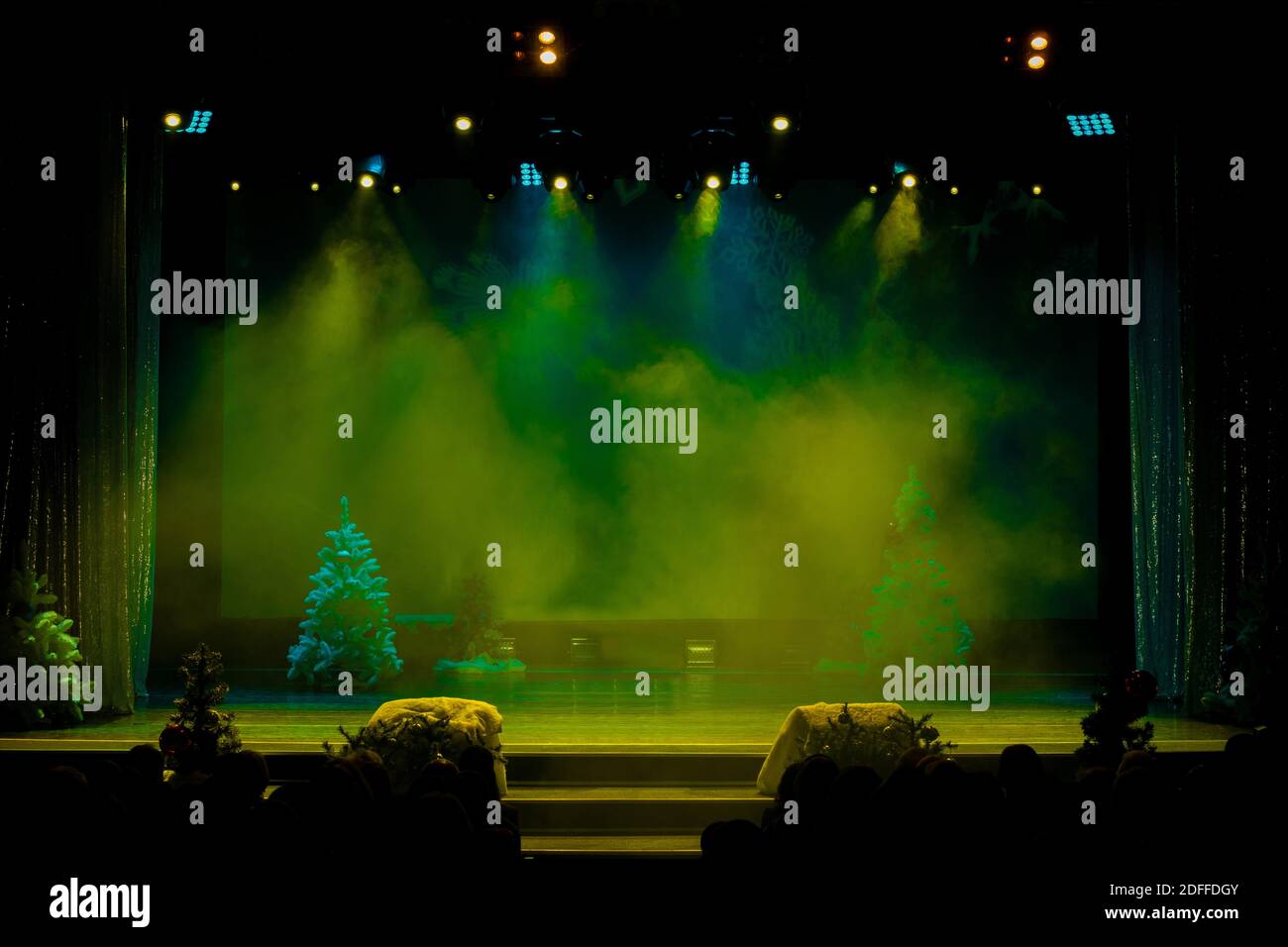 A theater stage with a curtain illuminated by stage light and smoke ...