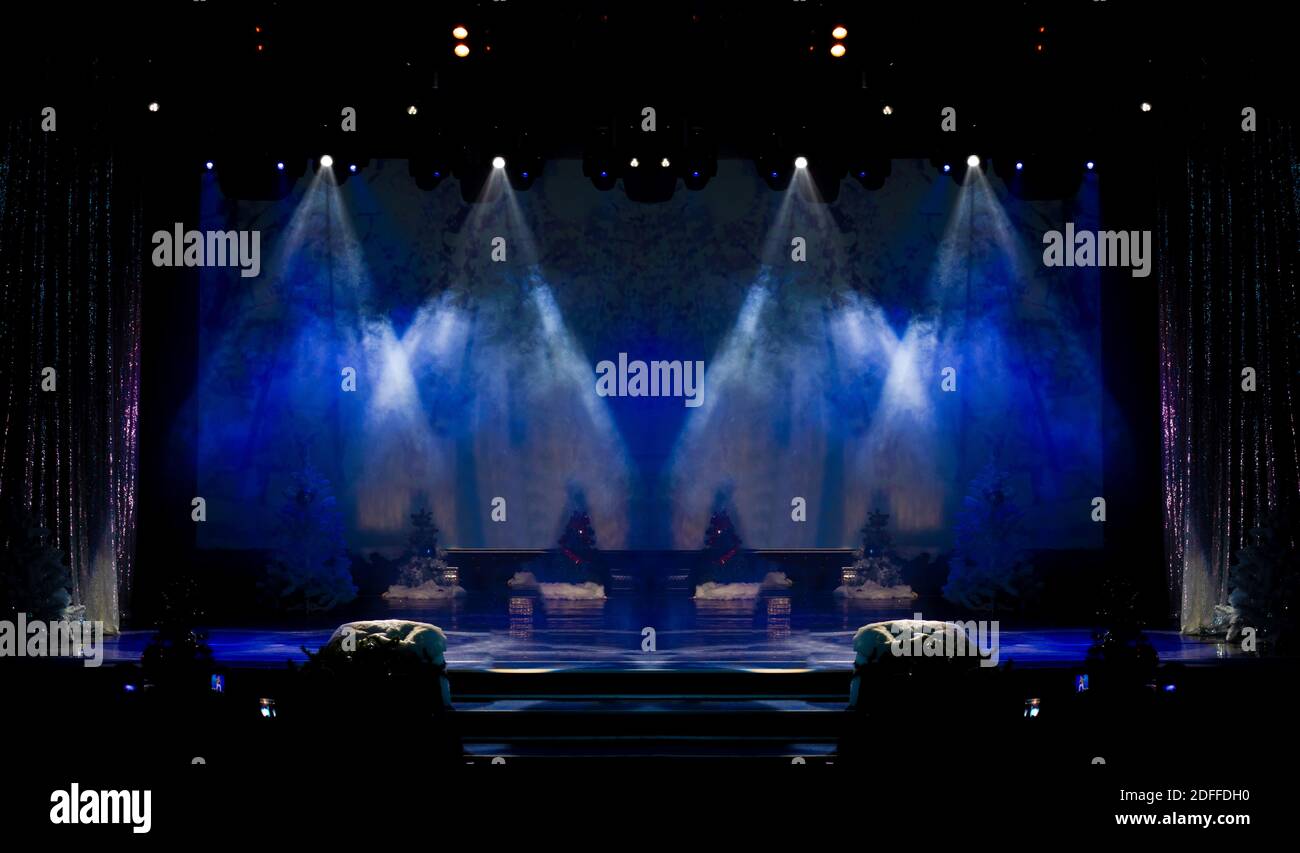 A theater stage with a curtain illuminated by stage light and smoke ...