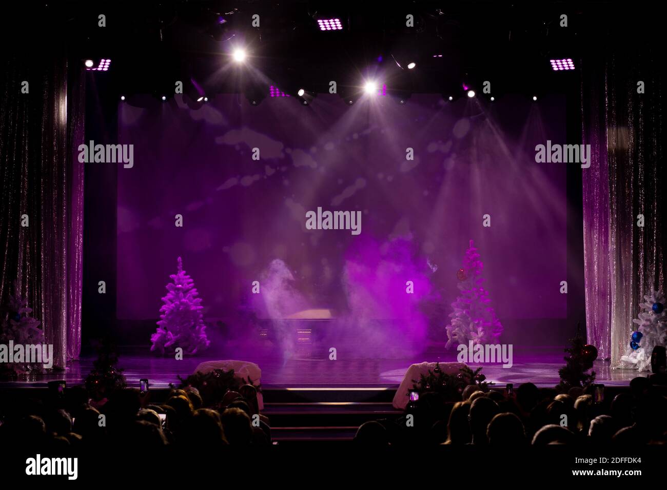 A theater stage with a curtain illuminated by stage light and smoke ...