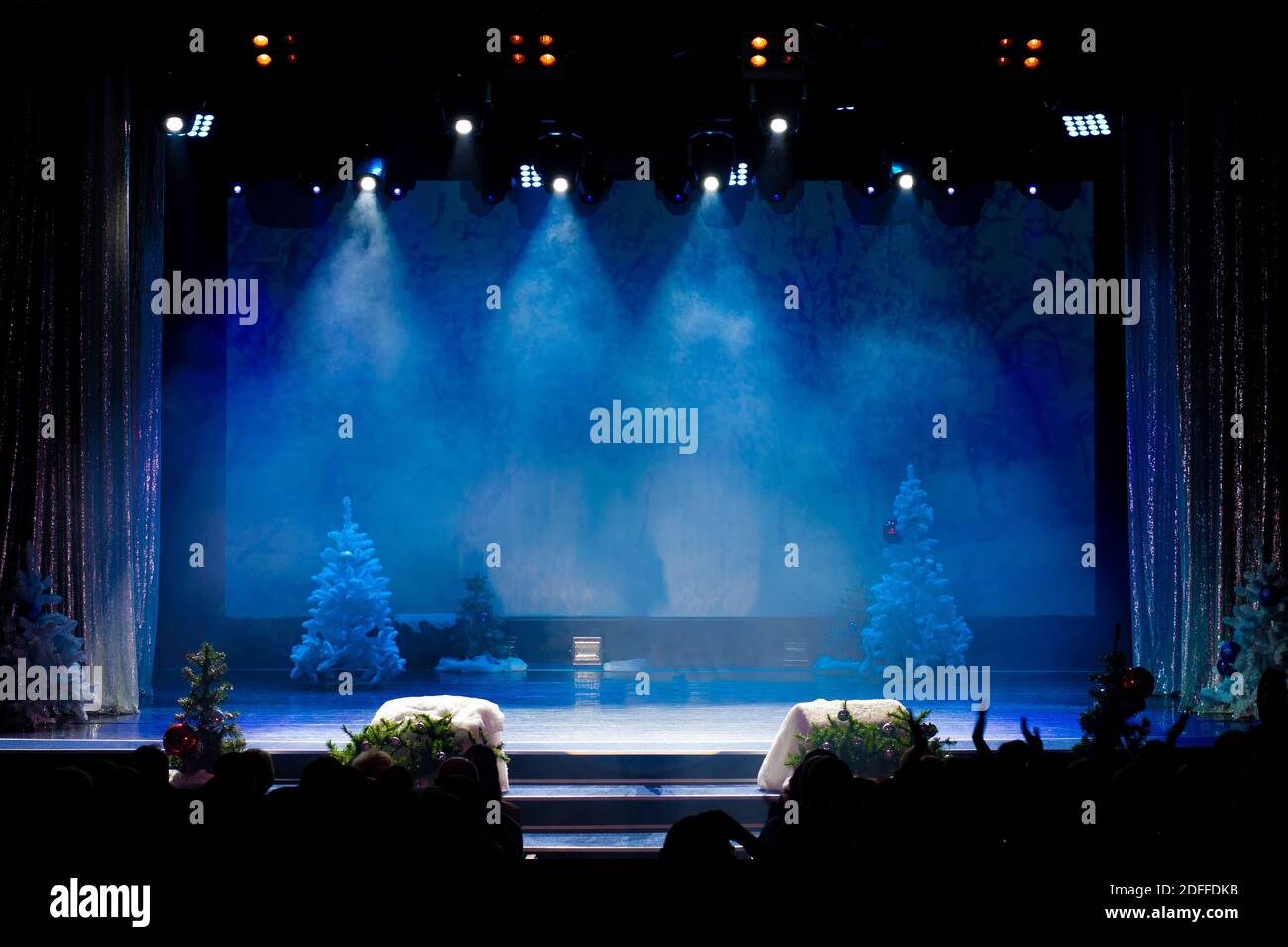 A theater stage with a curtain illuminated by stage light and smoke ...
