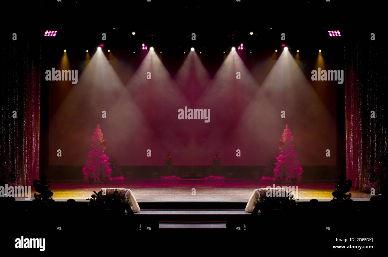 A theater stage with a curtain illuminated by stage light and smoke ...