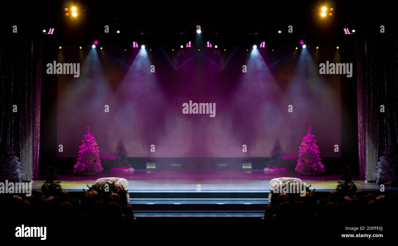 A theater stage with a curtain illuminated by stage light and smoke ...