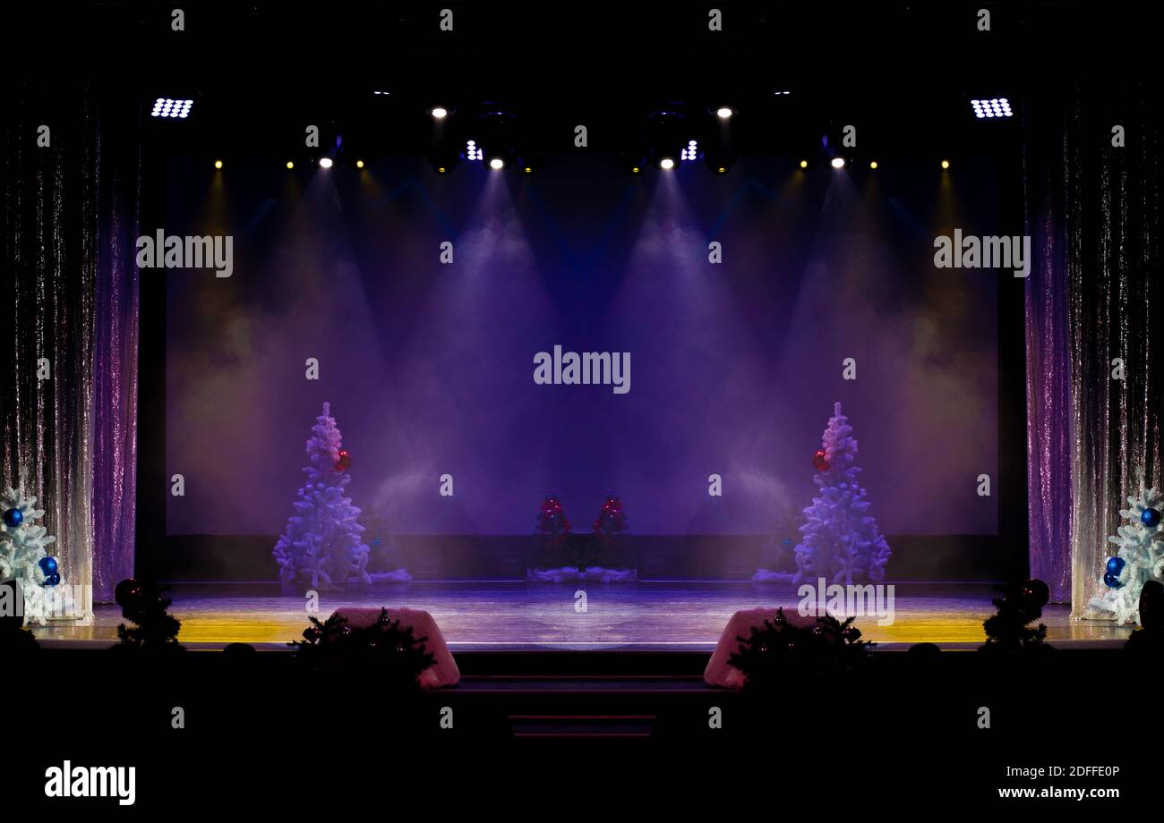 A theater stage with a curtain illuminated by stage light and smoke ...