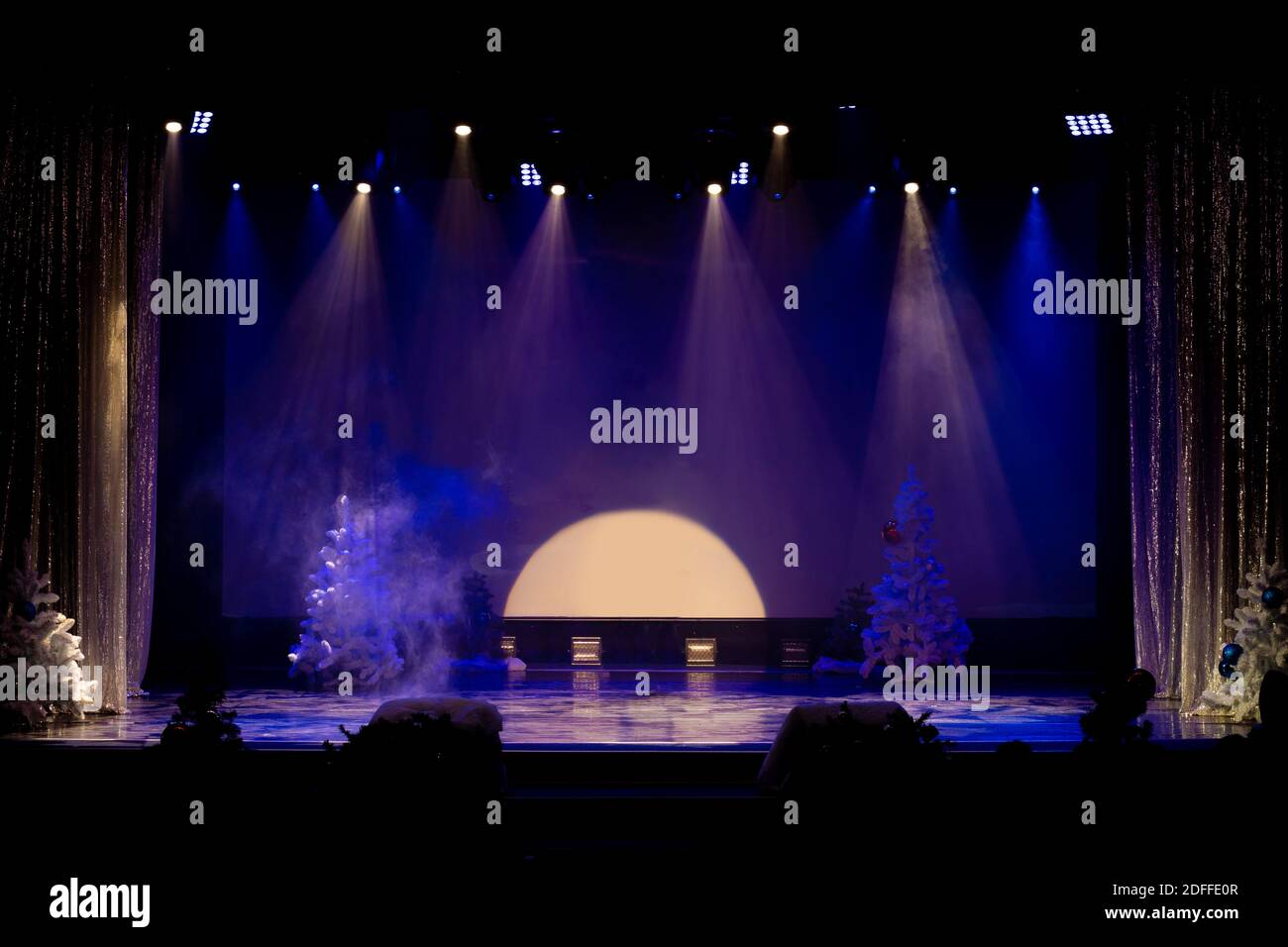 A theater stage with a curtain illuminated by stage light and smoke ...