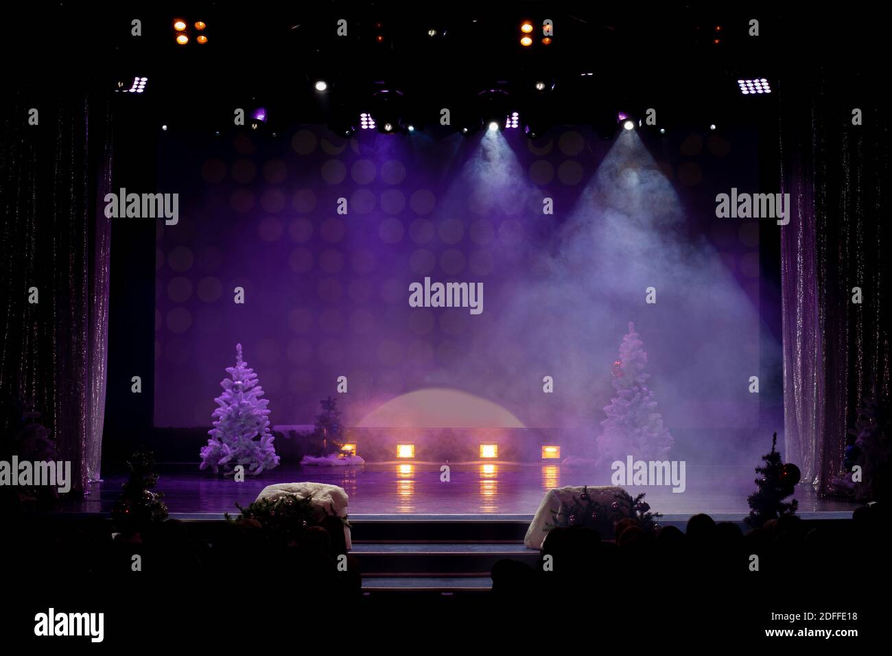 A theater stage with a curtain illuminated by stage light and smoke ...