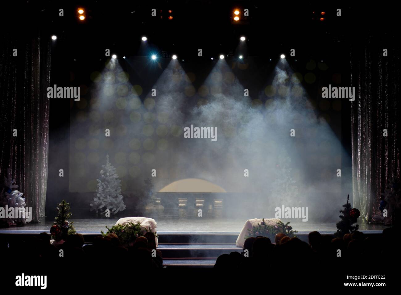 A theater stage with a curtain illuminated by stage light and smoke ...