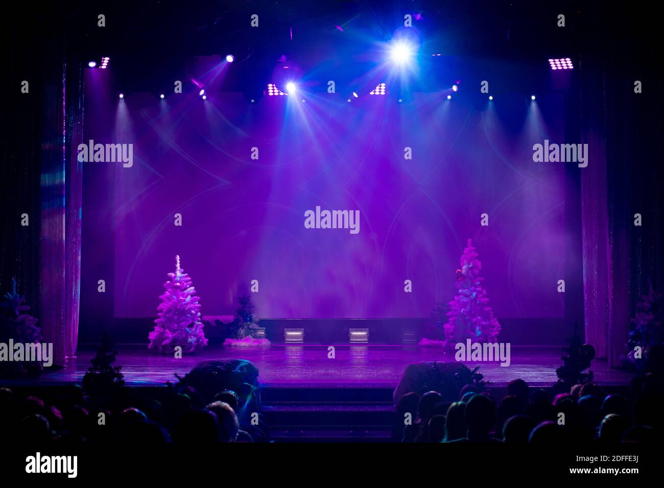 A theater stage with a curtain illuminated by stage light and smoke ...