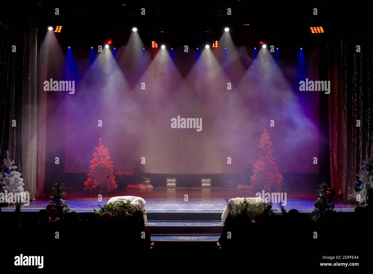 A theater stage with a curtain illuminated by stage light and smoke ...