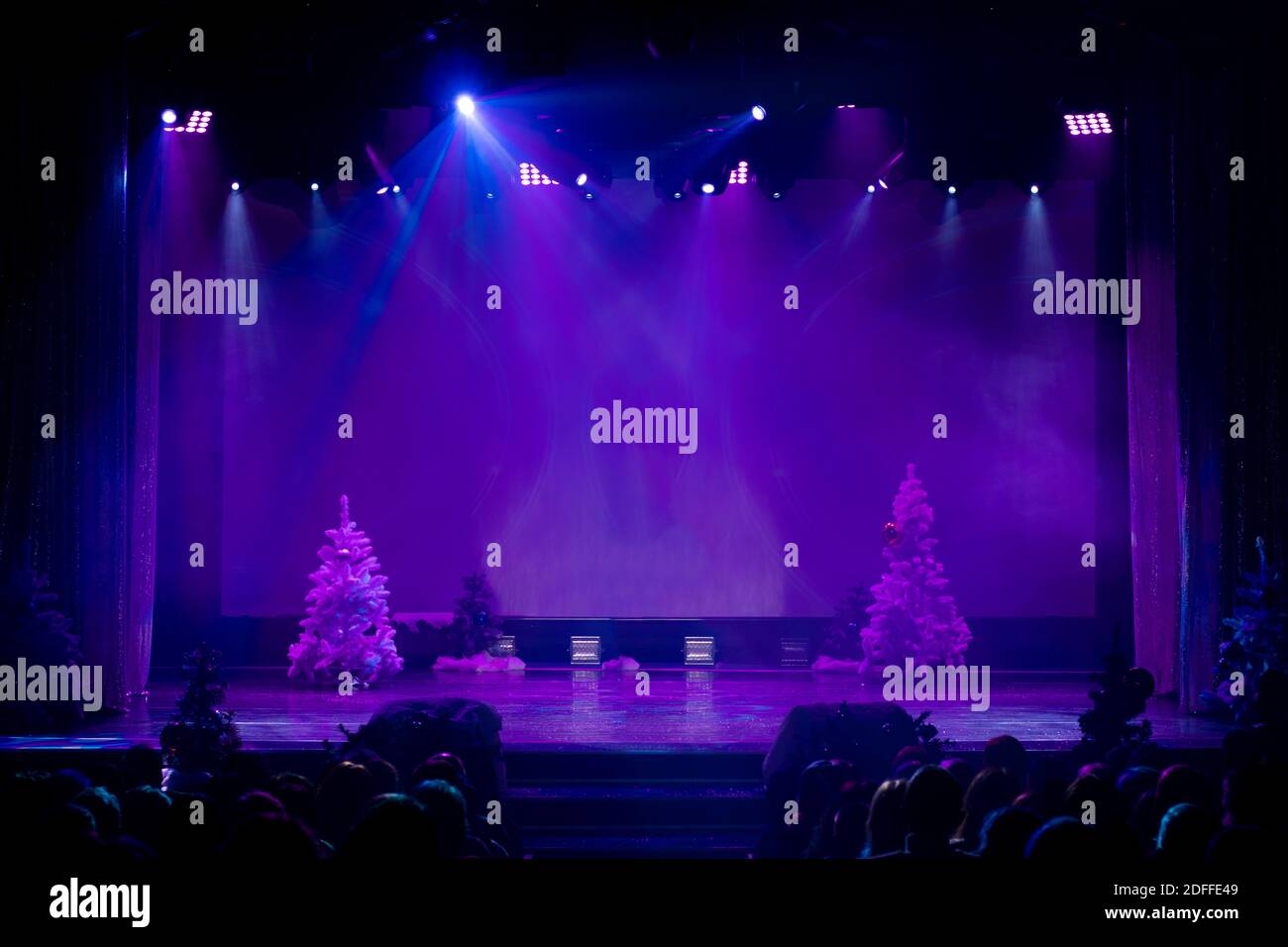 A theater stage with a curtain illuminated by stage light and smoke ...