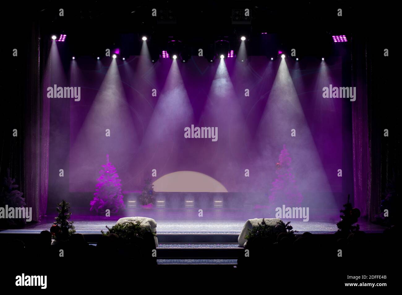 A theater stage with a curtain illuminated by stage light and smoke ...