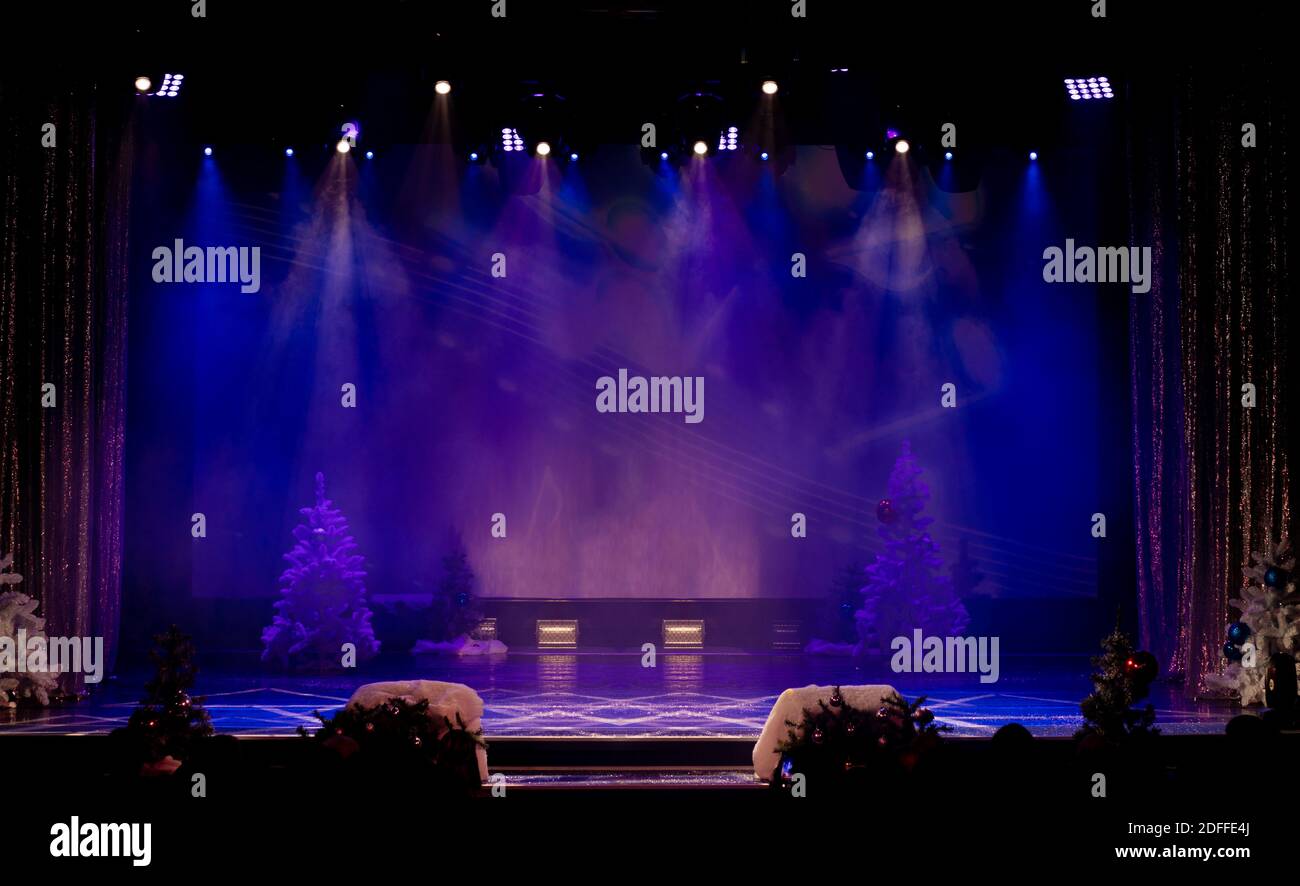 A theater stage with a curtain illuminated by stage light and smoke ...