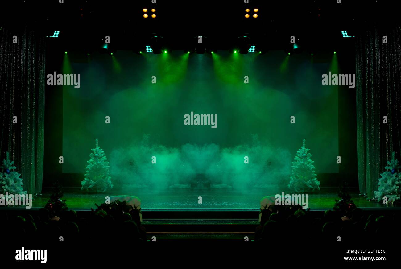A theater stage with a curtain illuminated by stage light and smoke ...