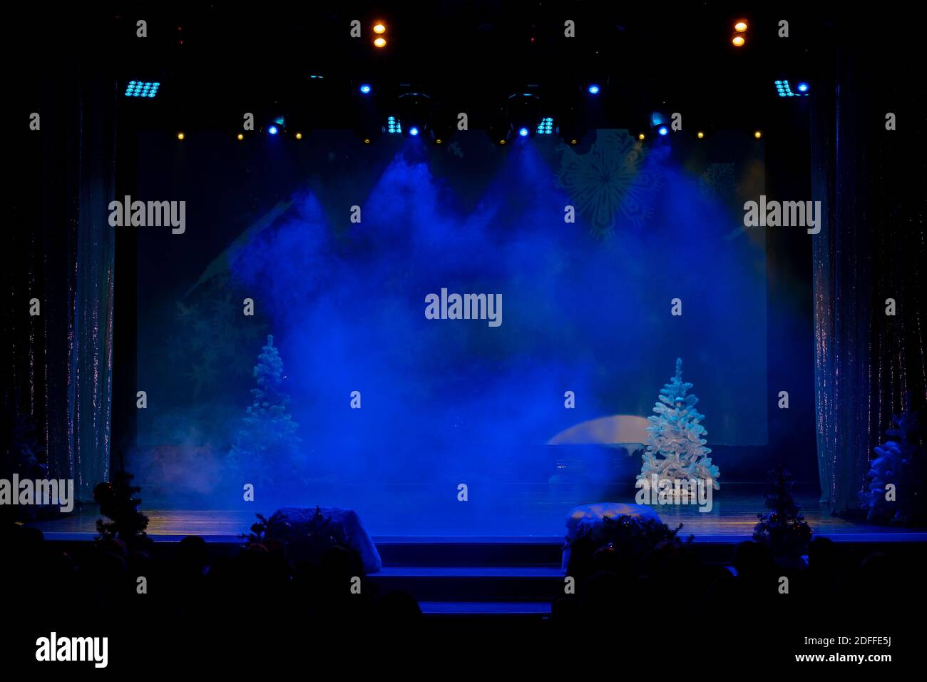 A theater stage with a curtain illuminated by stage light and smoke ...
