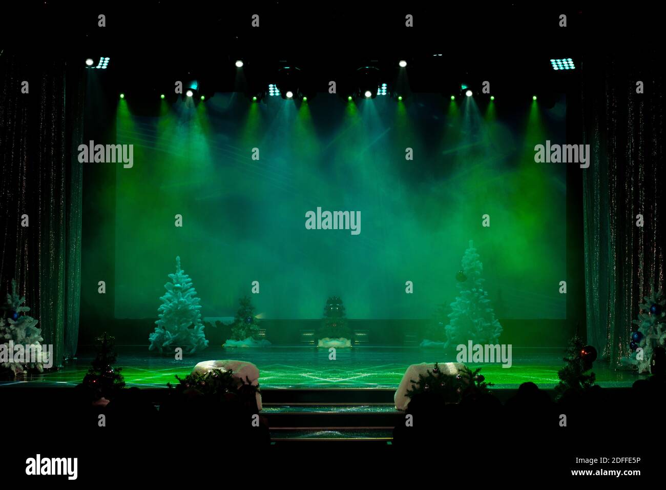 A theater stage with a curtain illuminated by stage light and smoke ...