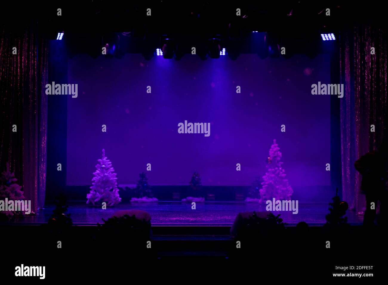 A theater stage with a curtain illuminated by stage light and smoke ...