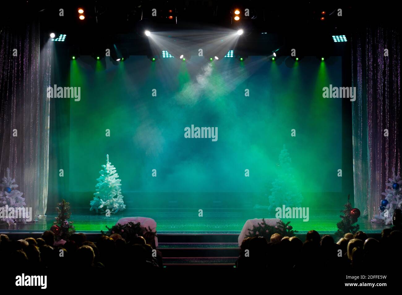 A theater stage with a curtain illuminated by stage light and smoke ...