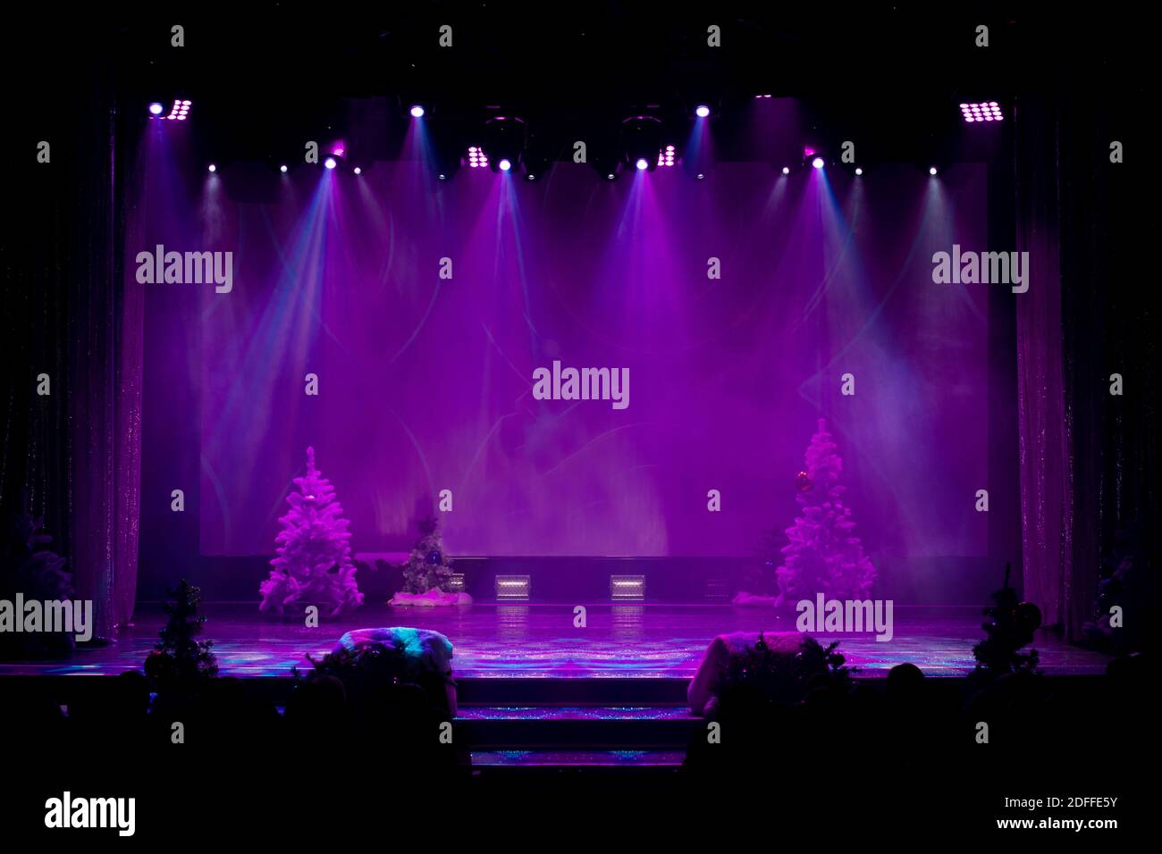 A theater stage with a curtain illuminated by stage light and smoke ...