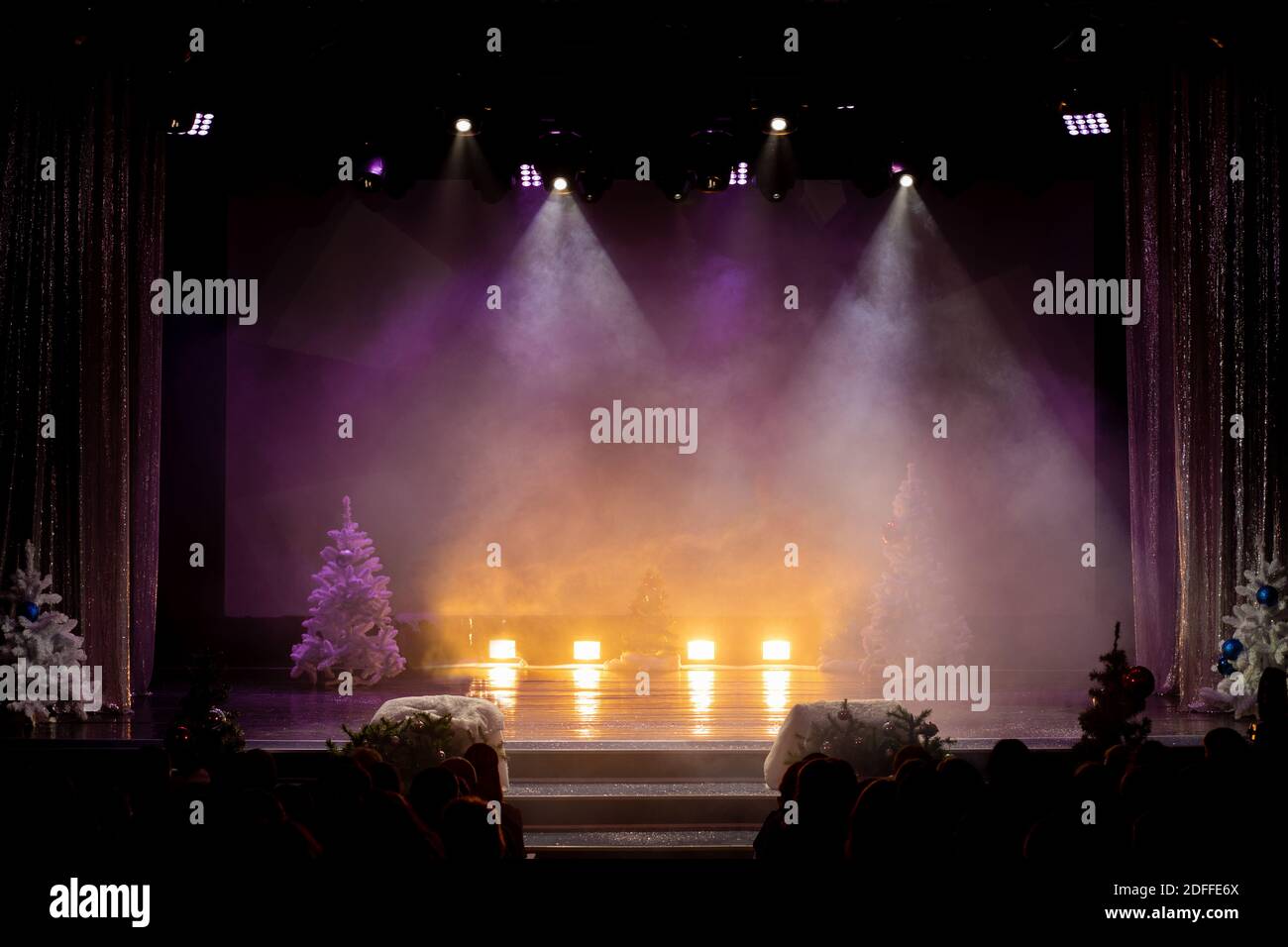 A theater stage with a curtain illuminated by stage light and smoke ...