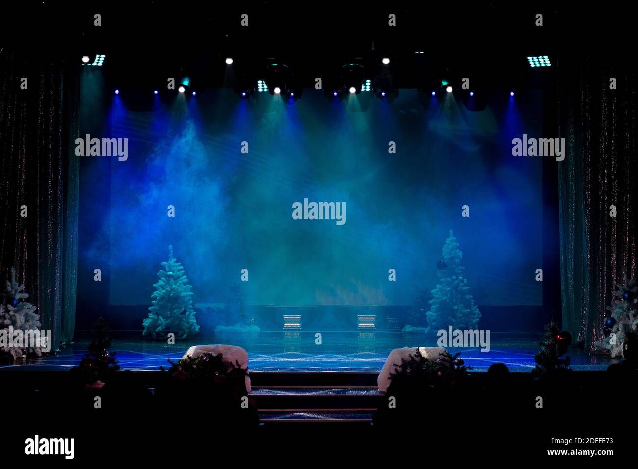A theater stage with a curtain illuminated by stage light and smoke ...