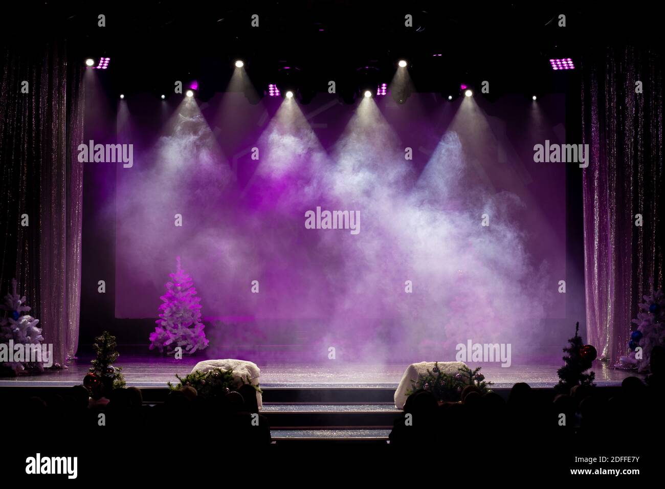 A theater stage with a curtain illuminated by stage light and smoke ...