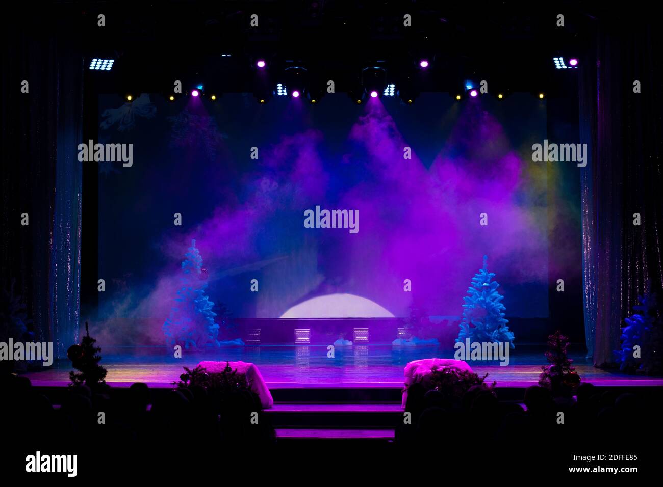 A theater stage with a curtain illuminated by stage light and smoke ...