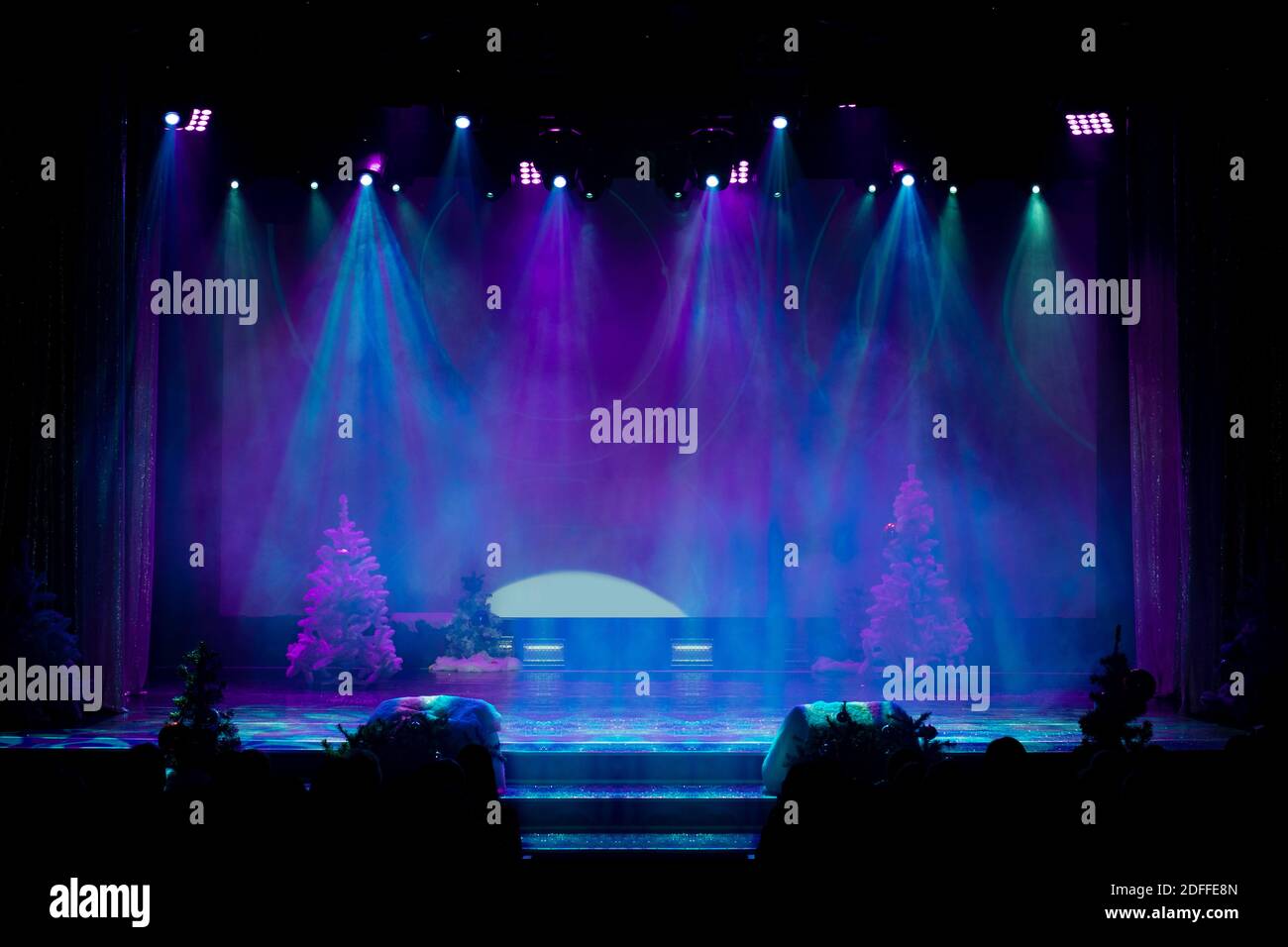 A theater stage with a curtain illuminated by stage light and smoke ...