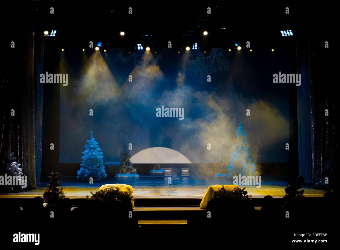A theater stage with a curtain illuminated by stage light and smoke ...
