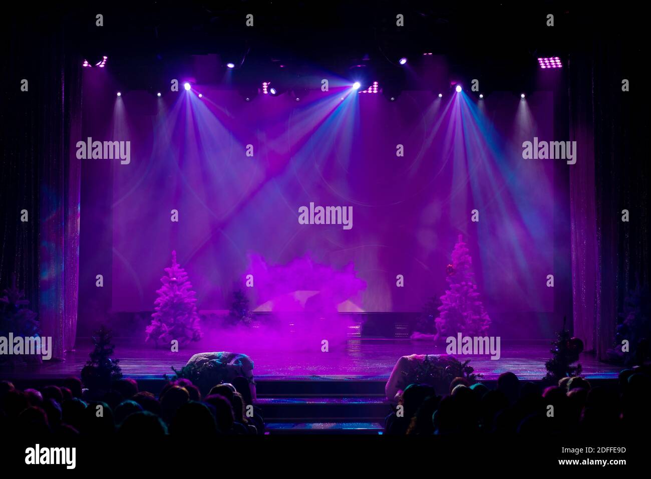 A theater stage with a curtain illuminated by stage light and smoke ...