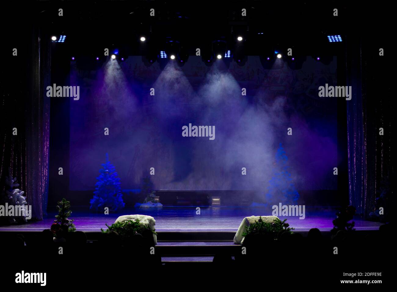 A theater stage with a curtain illuminated by stage light and smoke ...