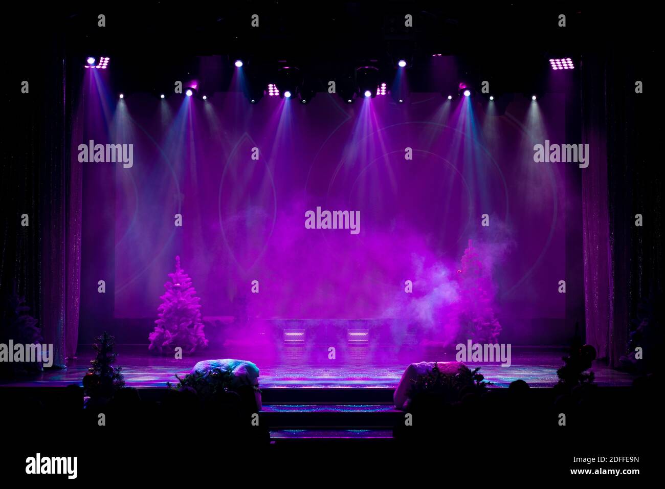 A theater stage with a curtain illuminated by stage light and smoke ...