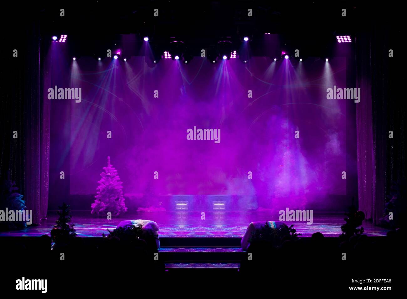 A theater stage with a curtain illuminated by stage light and smoke ...