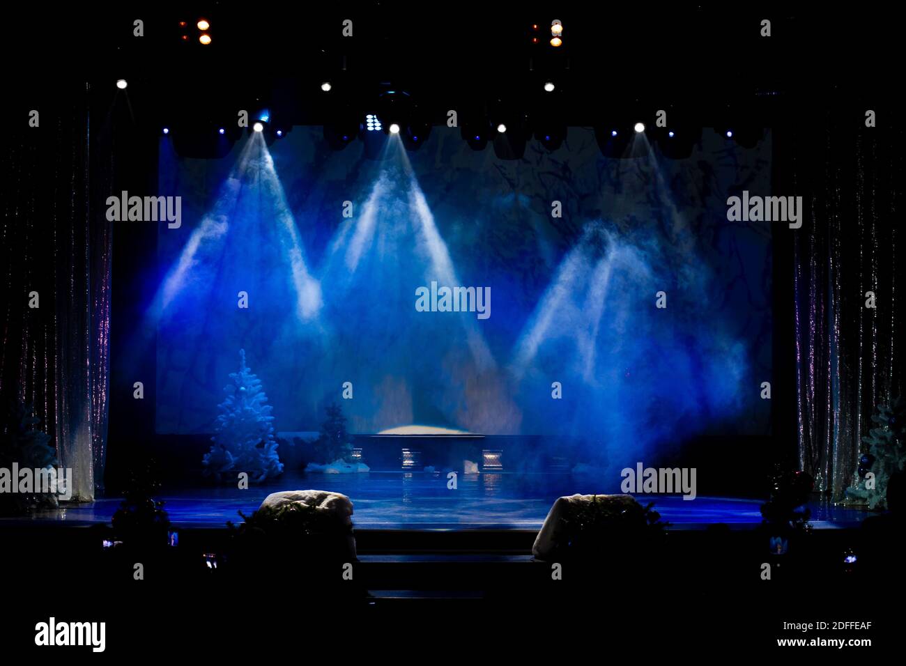 A theater stage with a curtain illuminated by stage light and smoke ...